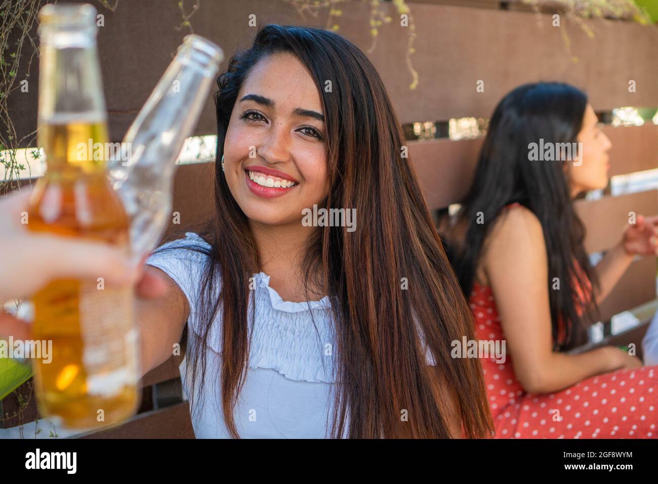 Latina girl toasting with a beer and her friends in the background ...