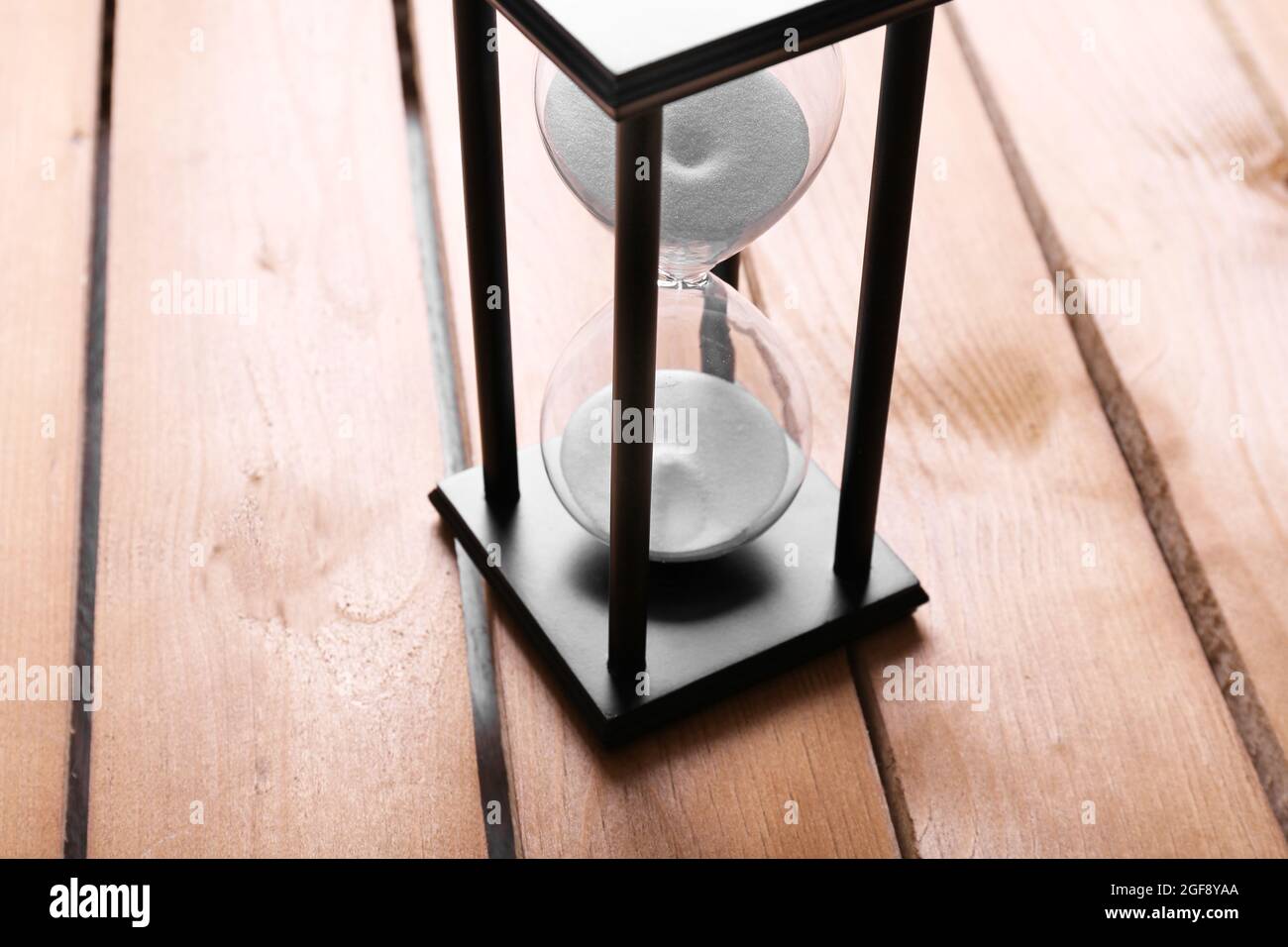 Black sand glass on wooden background Stock Photo - Alamy