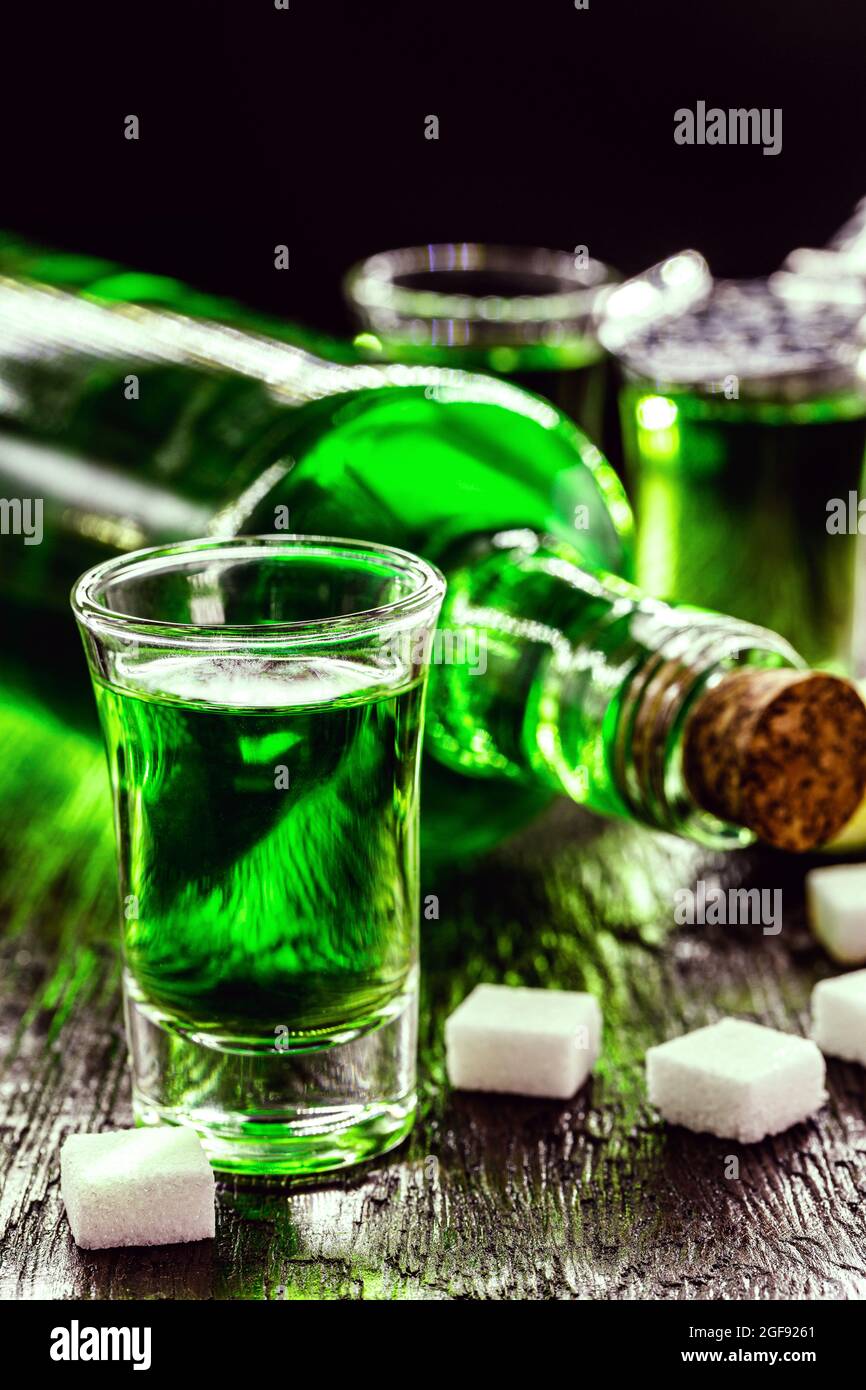 absinthe in glass with lemon slices on dark background with white sugar ...