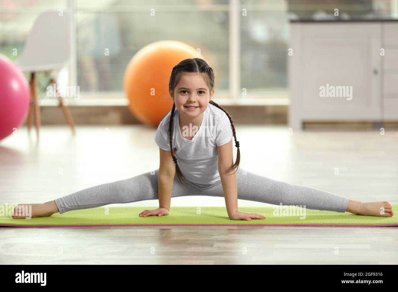 Little cute girl stretching herself on a mat indoor Stock Photo - Alamy