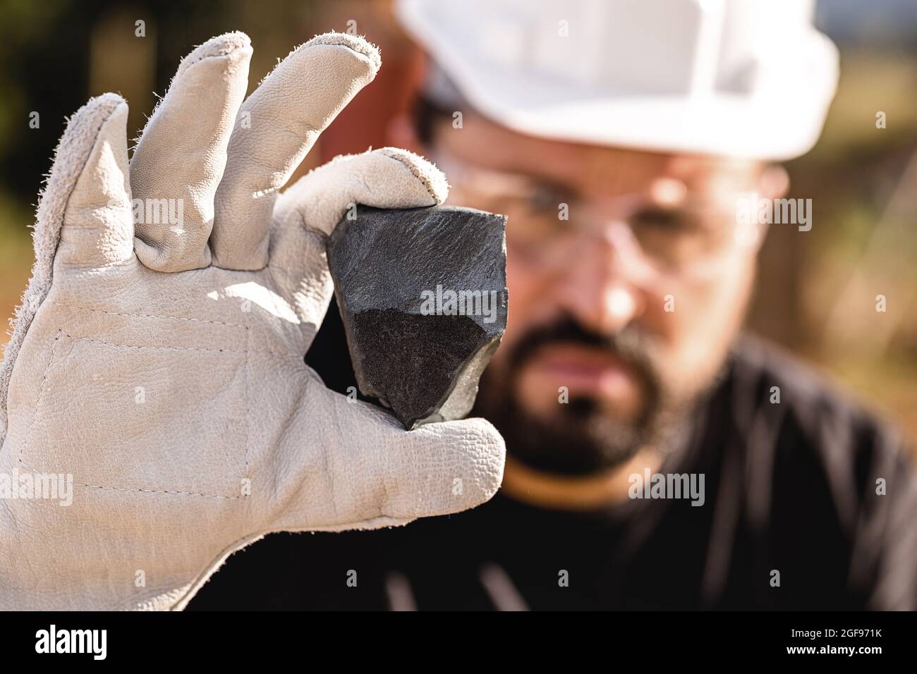 rough iron stone, ferrous metal nugget mined. Miner holding hematitia ...