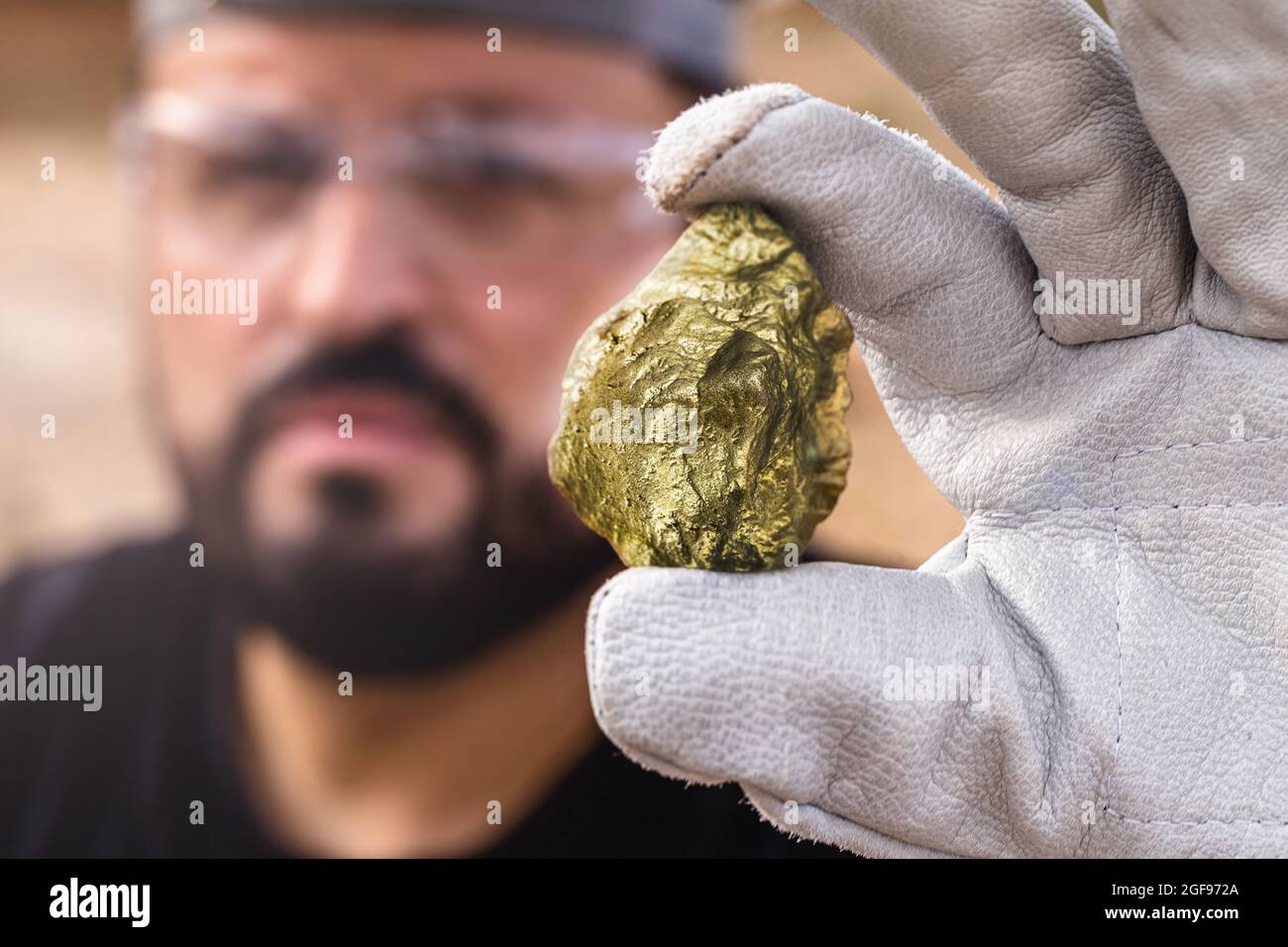 miner holding gold nugget, point focus on the gemstone. Mineral ...