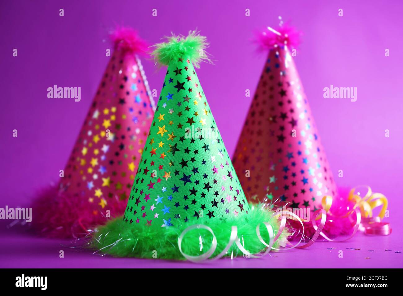 Funny party hats on purple background Stock Photo - Alamy