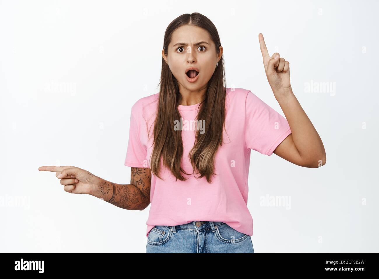 Shocked and worried woman pointing fingers left and up, showing two ...