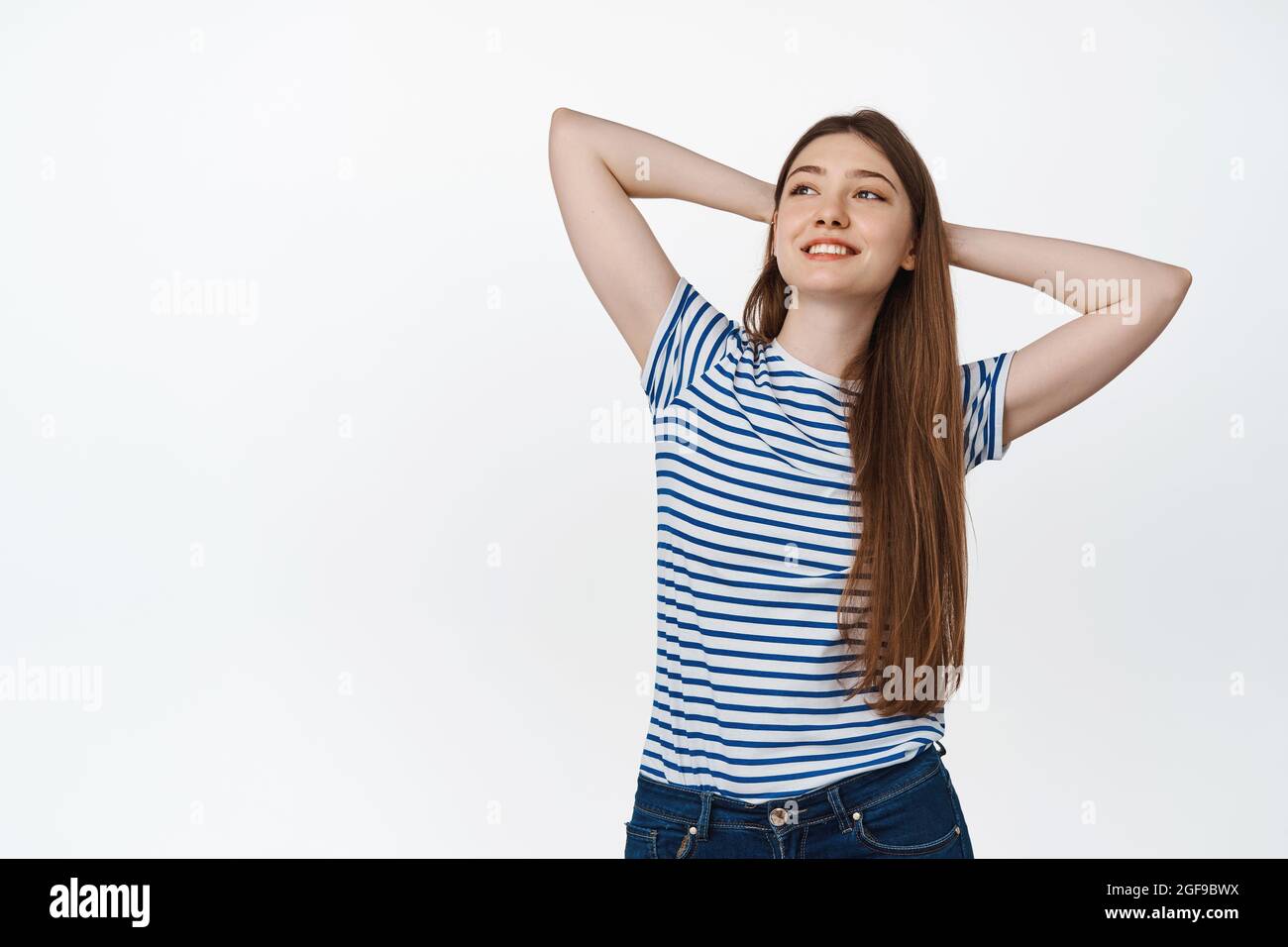 Image of young woman looking satisfied, hold hands behind head and ...