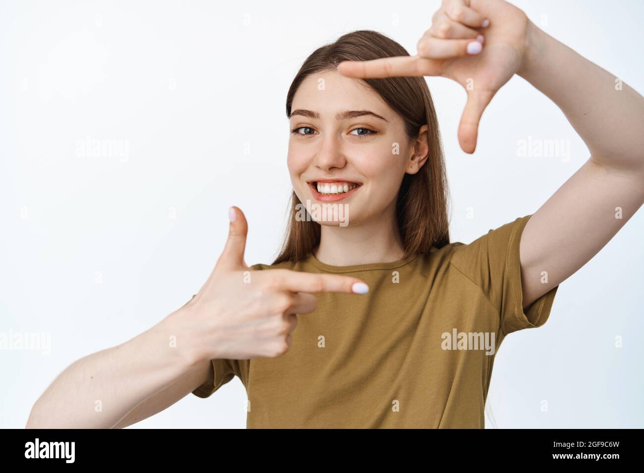 Snap. Smiling happy girl taking picture, looking through hand frame ...