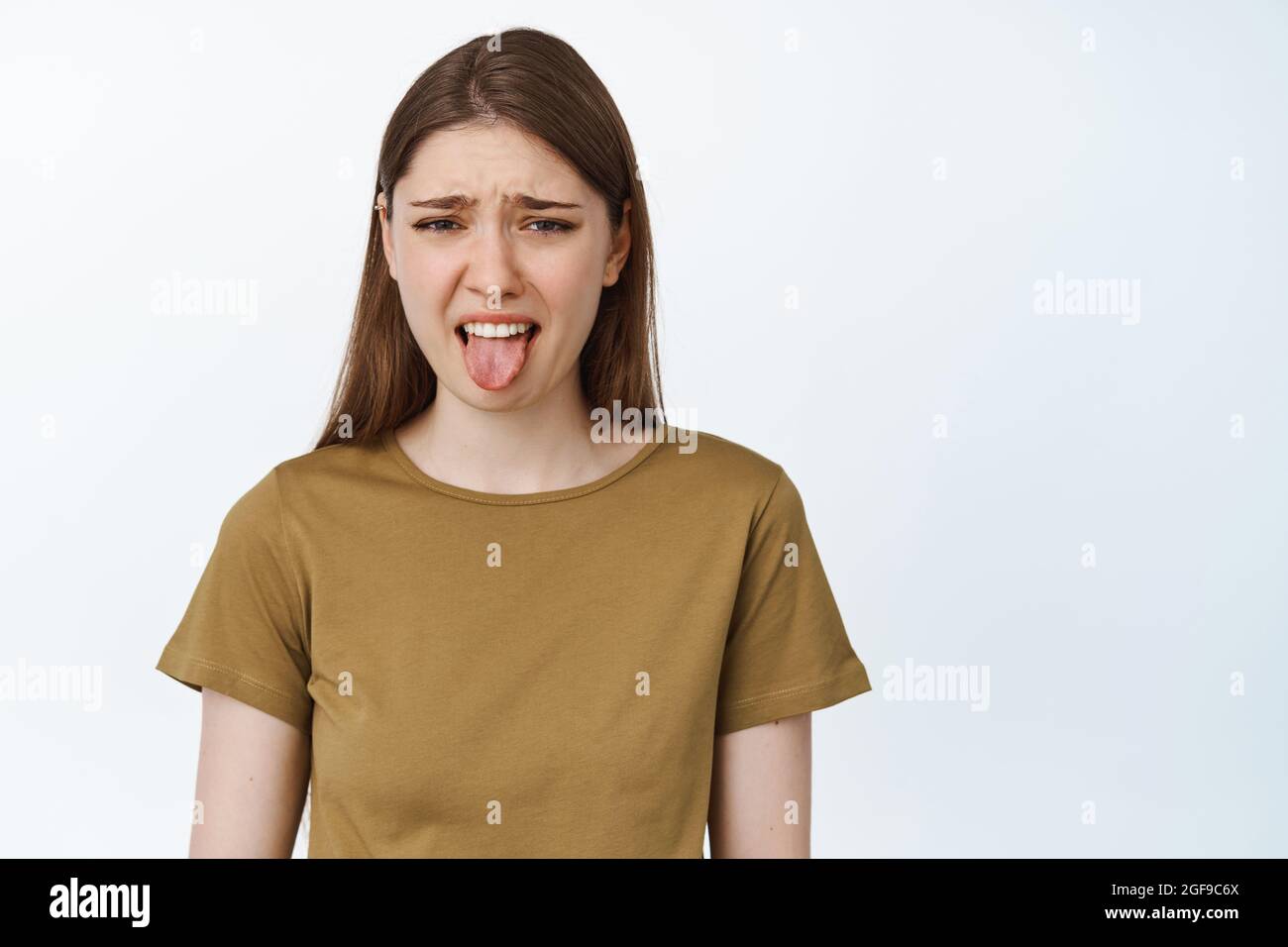 Young woman stick tongue from dislike, disgusted with bad taste, smth ...