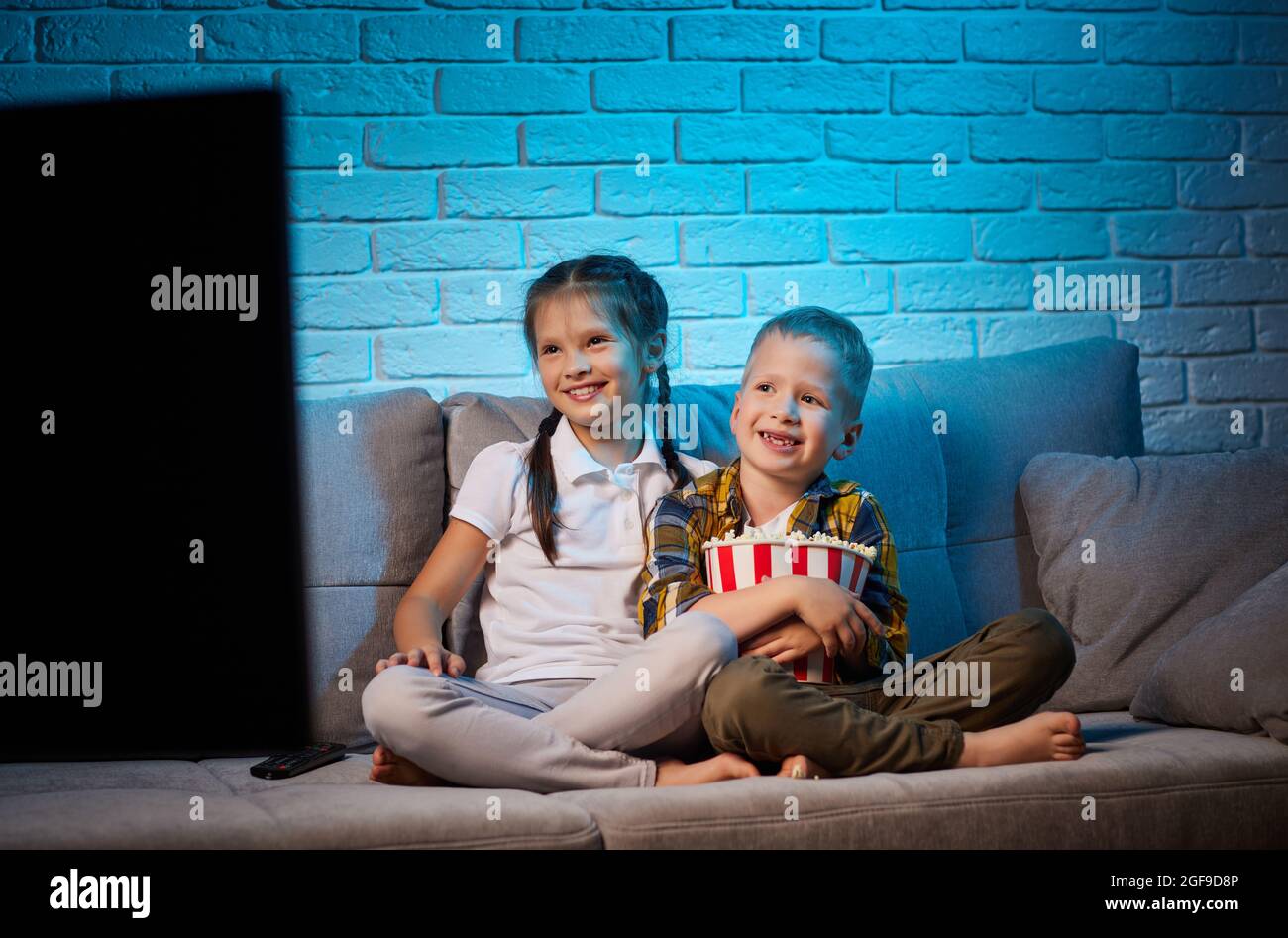 two children with remote control watching TV Stock Photo - Alamy