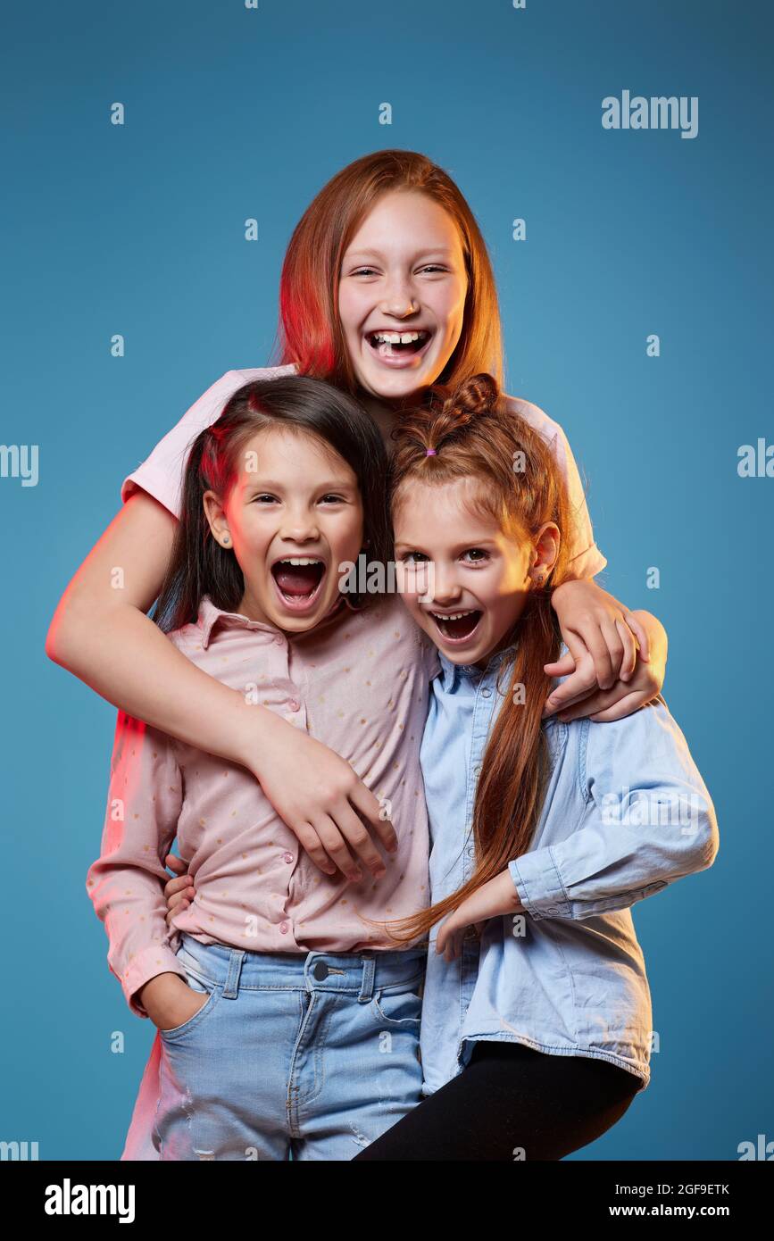 three kids girls standing together on blue background Stock Photo - Alamy
