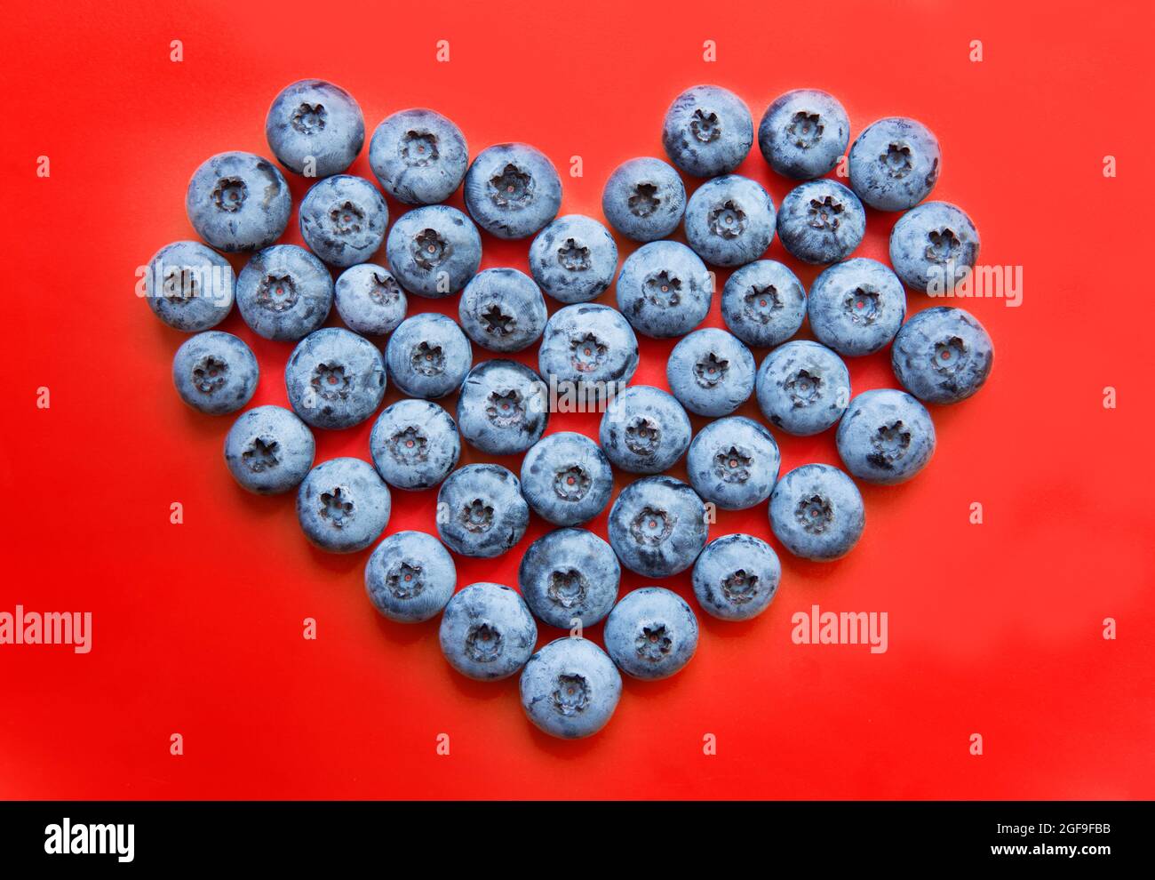 Heart made from fresh blueberries on a red background. Healthy eating ...