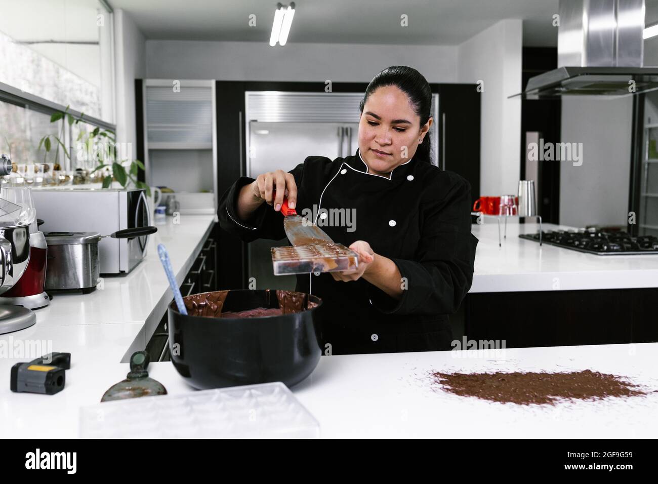 latin woman pastry chef wearing black uniform in process of preparing ...