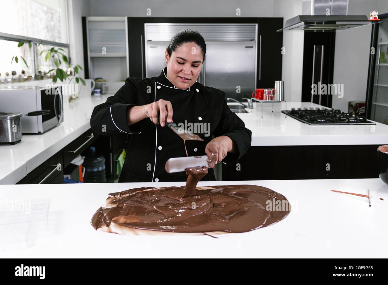latin woman pastry chef wearing black uniform in process of preparing ...