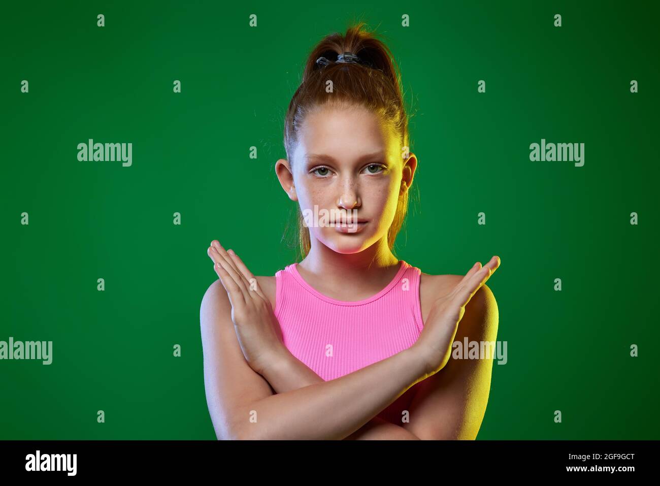 teenager showing stop gesture on green background Stock Photo - Alamy