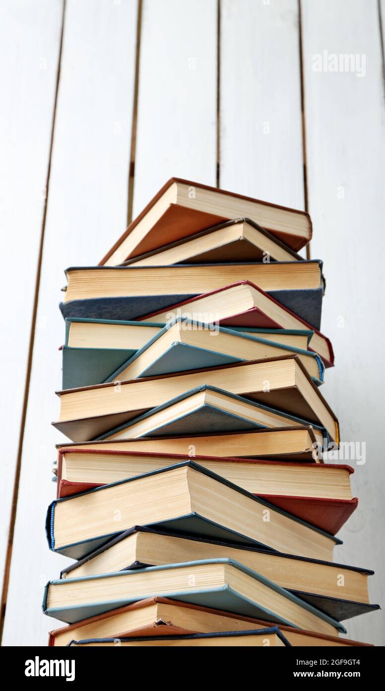 High stack of books on white wooden wall background Stock Photo - Alamy