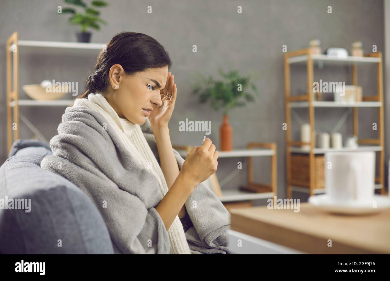 Woman who has flu or cold fever looking at thermometer after taking her ...