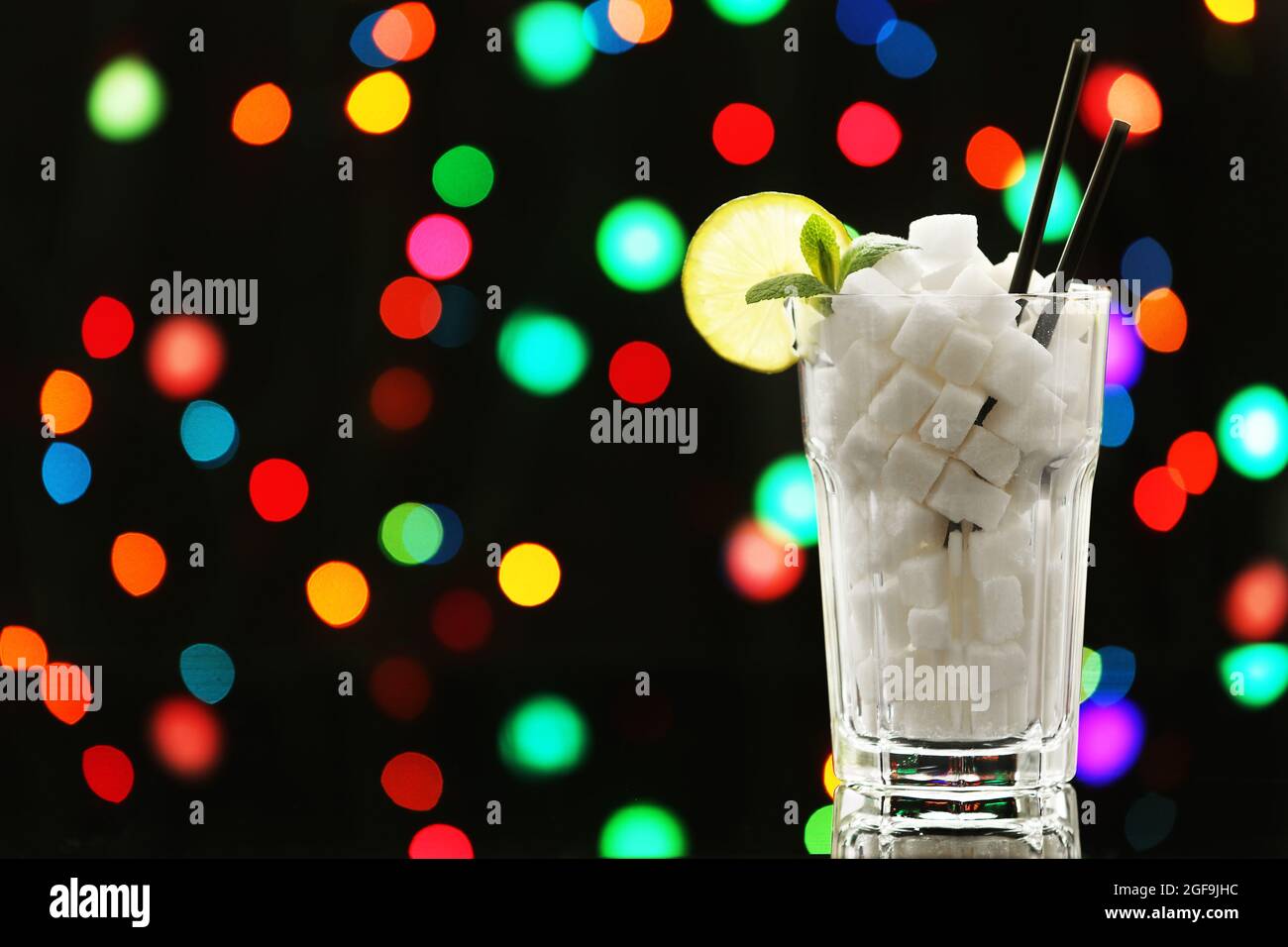 Highball glass with lump sugar on dark bokeh background Stock Photo - Alamy