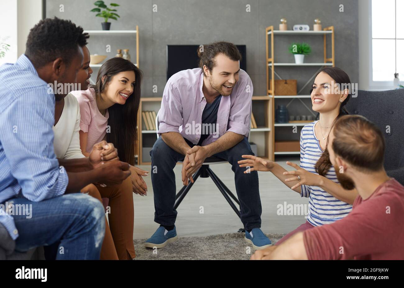 Group of young cheerful diverse people communicate with each other and ...