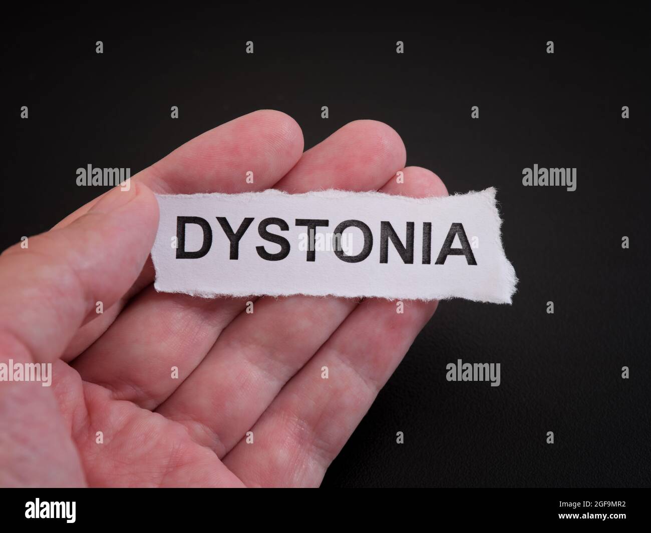 Dystonia. A man holding a torn piece of paper with the word Dystonia on ...