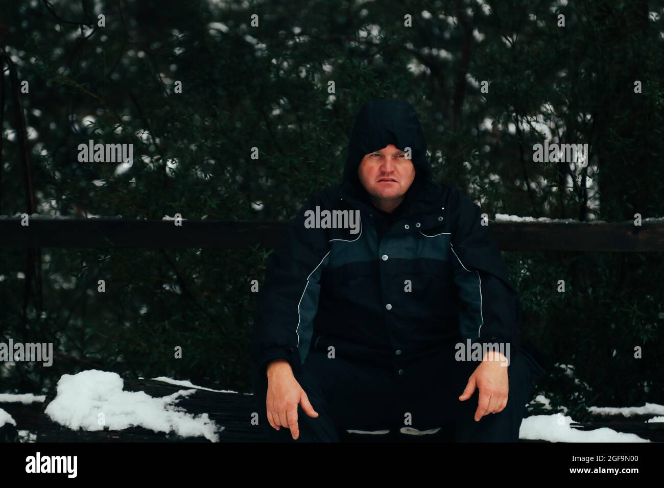 Australian grumpy man sitting outdoors in snowy weather, during ...