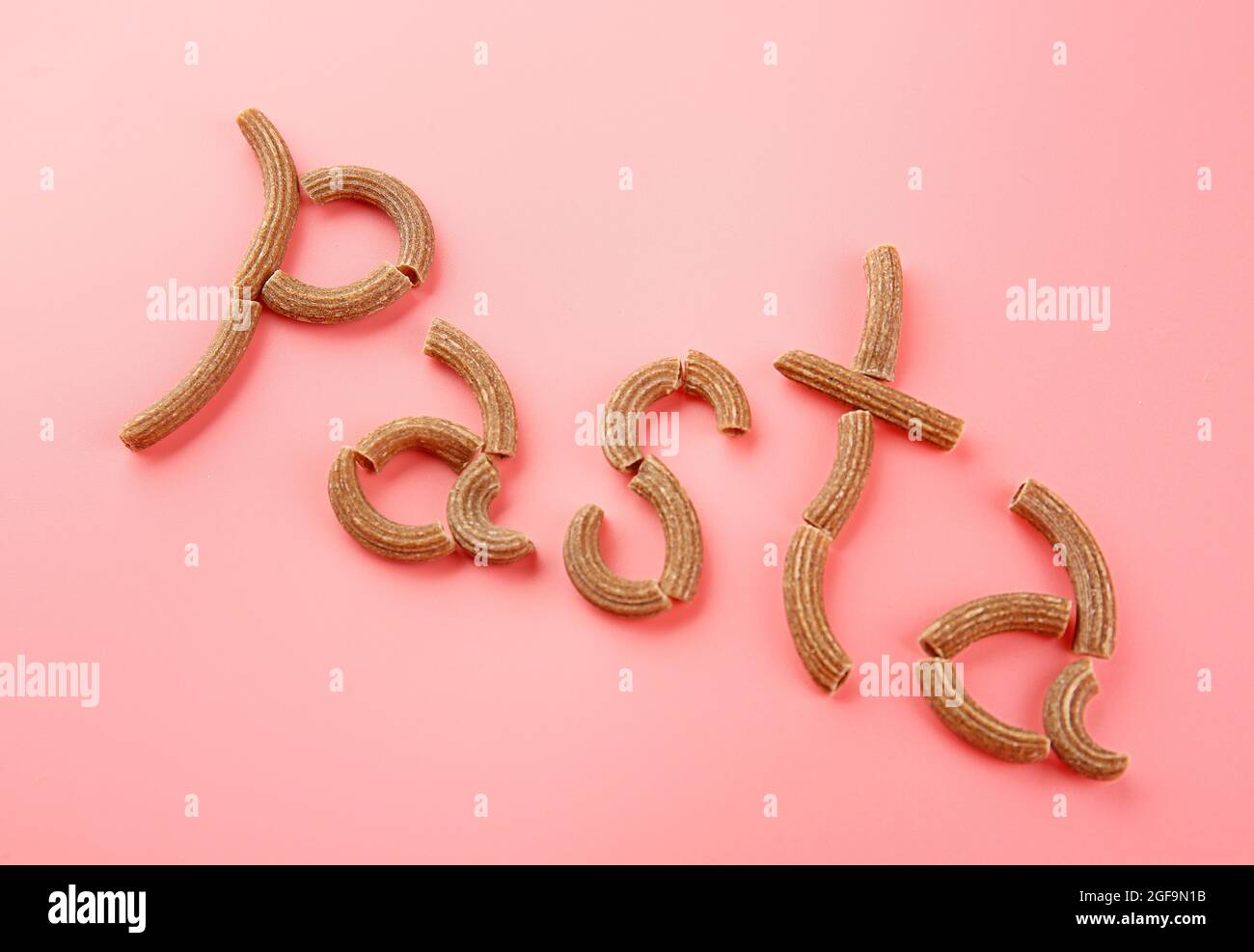 Pasta word made with brown macaroni on pink background Stock Photo - Alamy