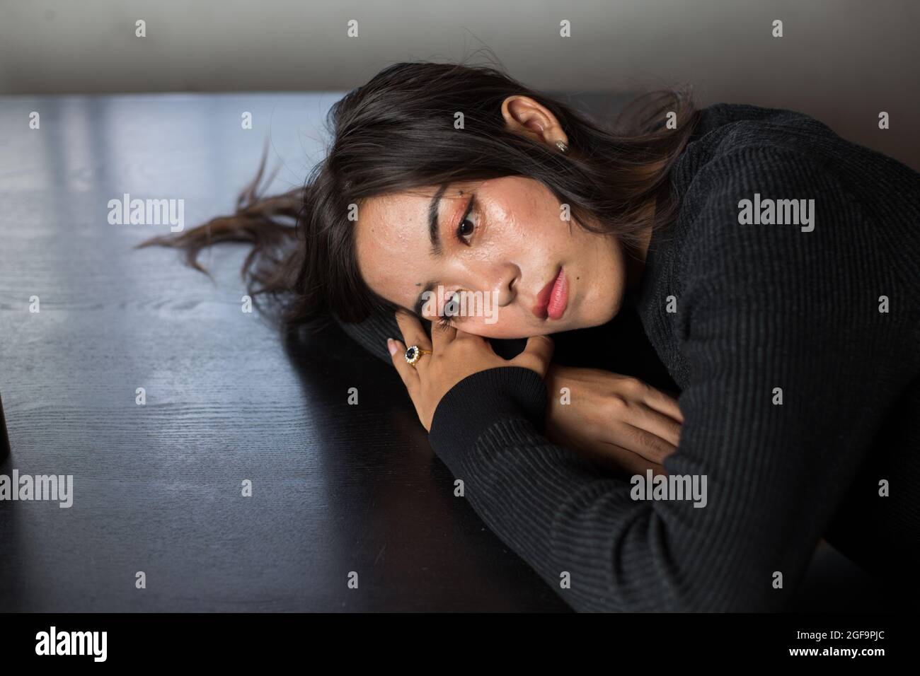 Beautiful young Asian woman in black resting her head on the table Stock Photo - Alamy