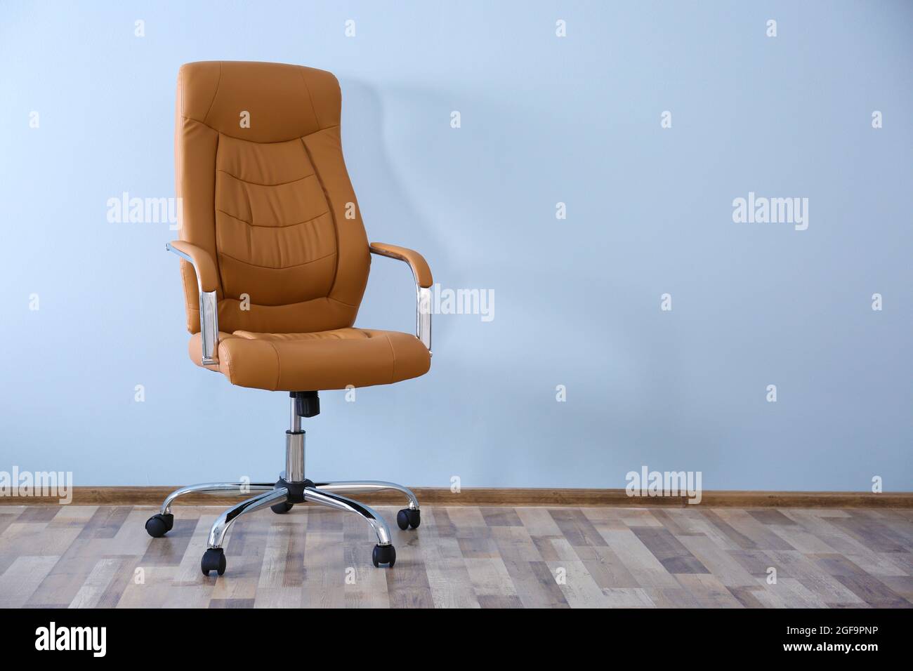 New office chair on wall background Stock Photo - Alamy
