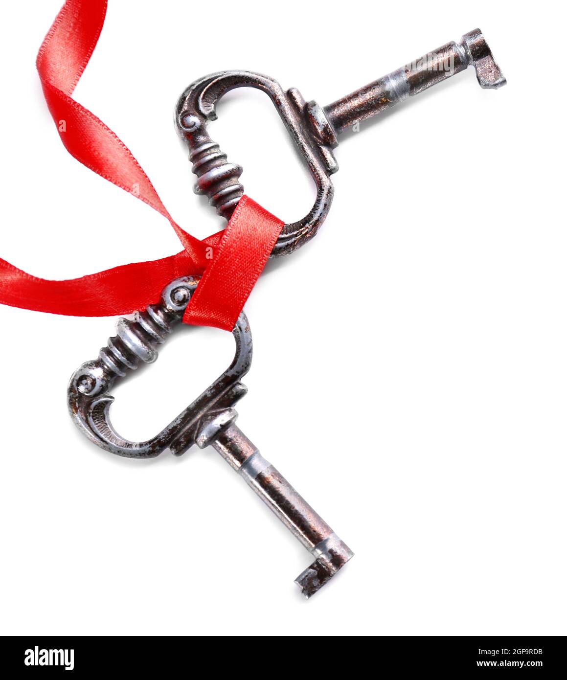 Two vintage keys connected with a red ribbon on a white background ...