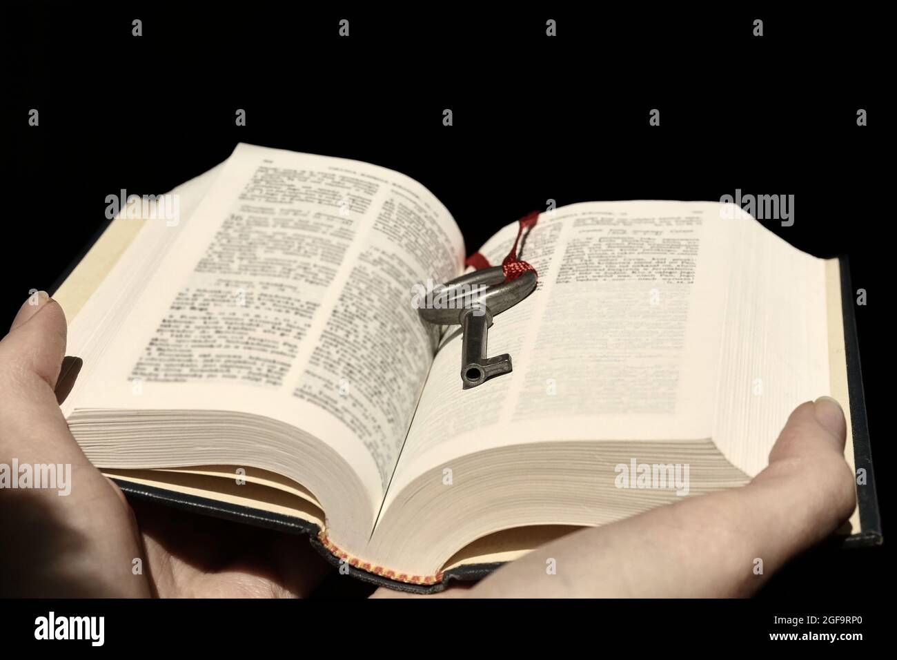 Hands holding a book with vintage key on black background Stock Photo ...