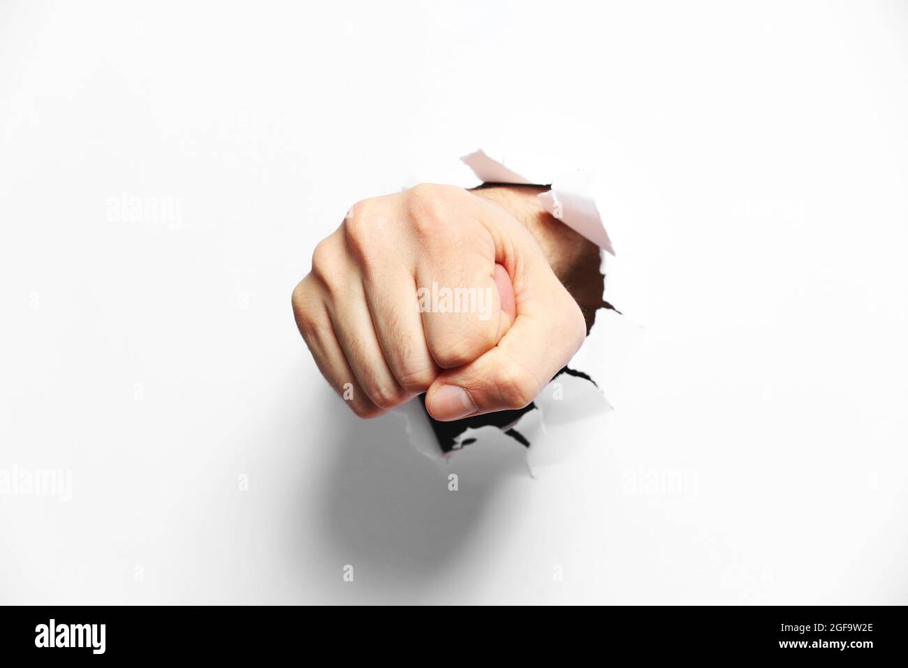 Male fist punching through paper, isolated on white Stock Photo - Alamy