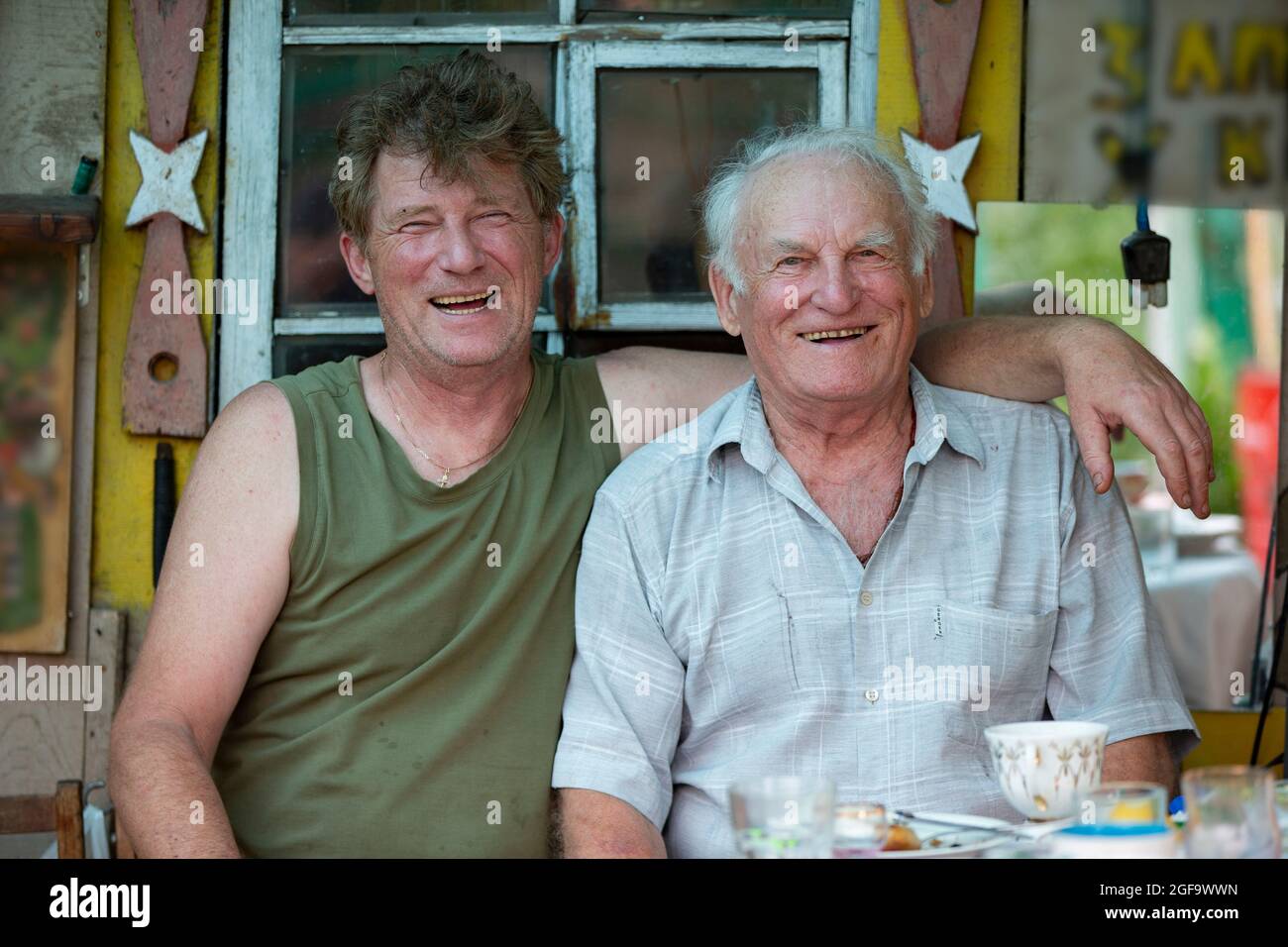 An adult son and an old man father have fun laughing, hugging and ...