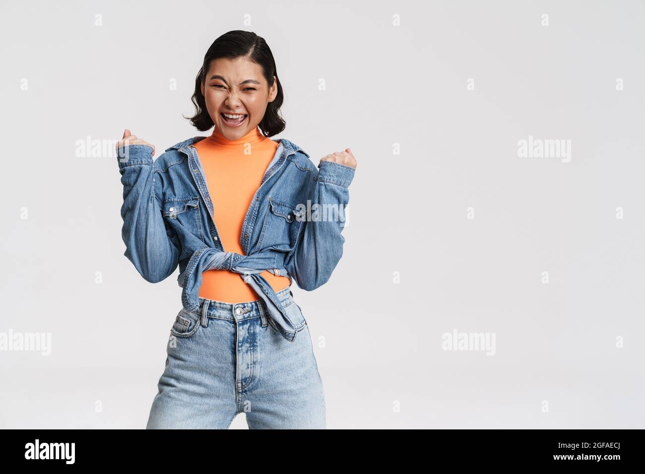 Young asian brunette woman screaming while making winner gesture ...