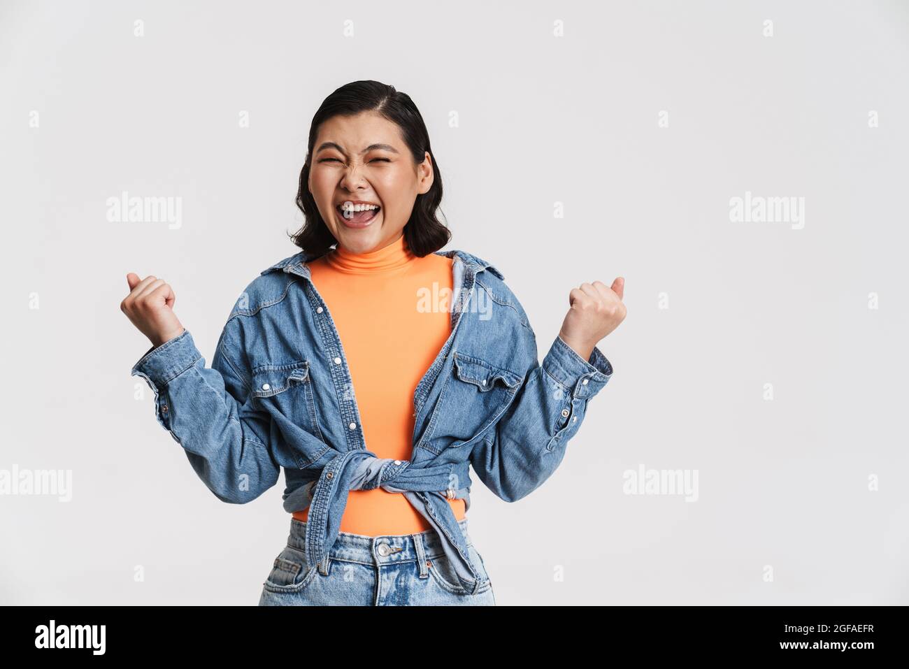 Young asian brunette woman screaming while making winner gesture ...