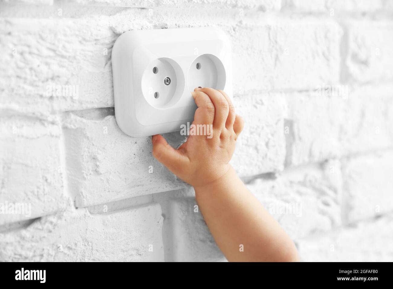 Little baby playing with socket on the wall Stock Photo - Alamy