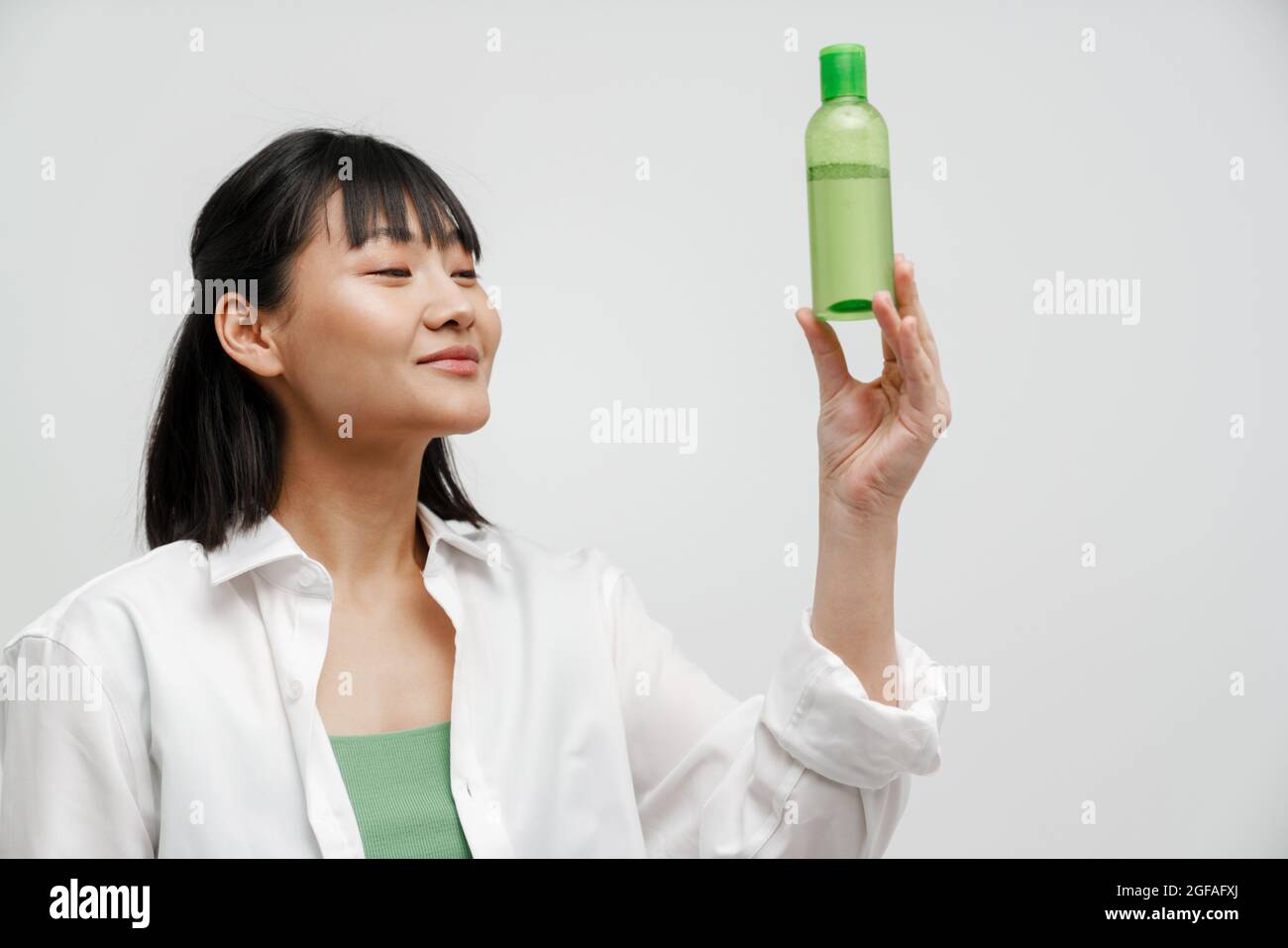 Young asian woman smiling while showing facial lotion isolated over ...