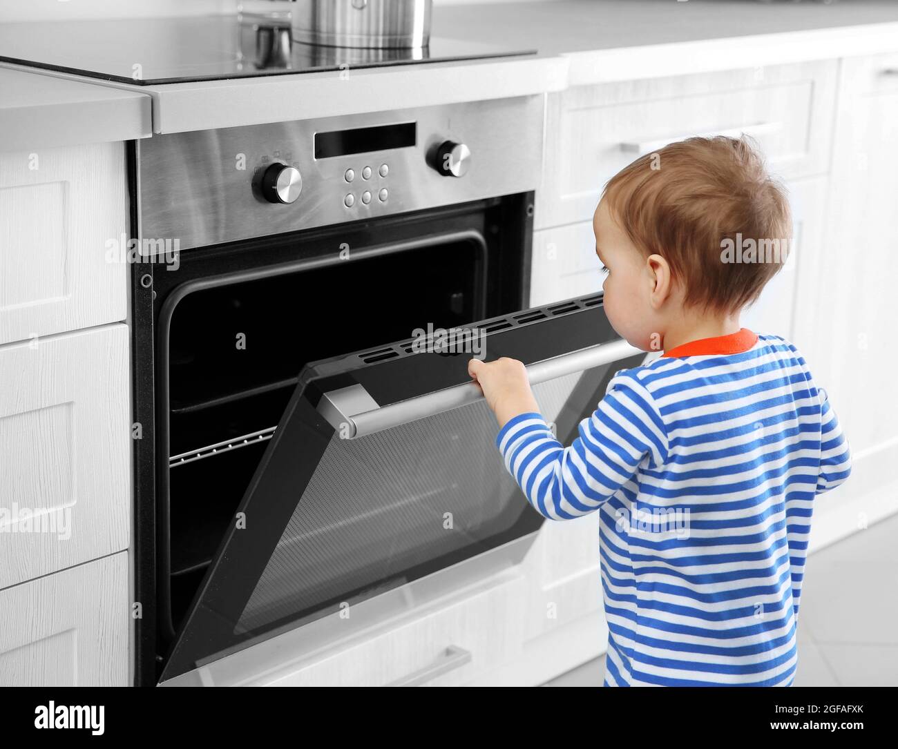 Little child playing with oven in the kitchen Stock Photo - Alamy