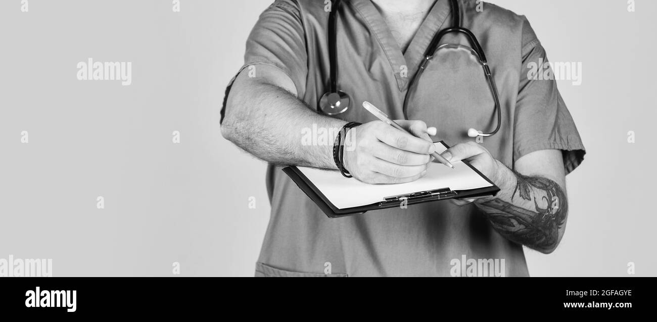 nurse writing some data into the folder of papers. male hospital ...