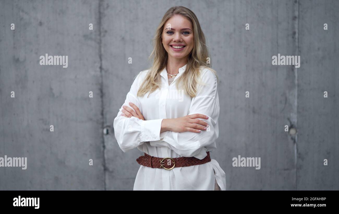 Positive woman standing against wall Stock Photo - Alamy