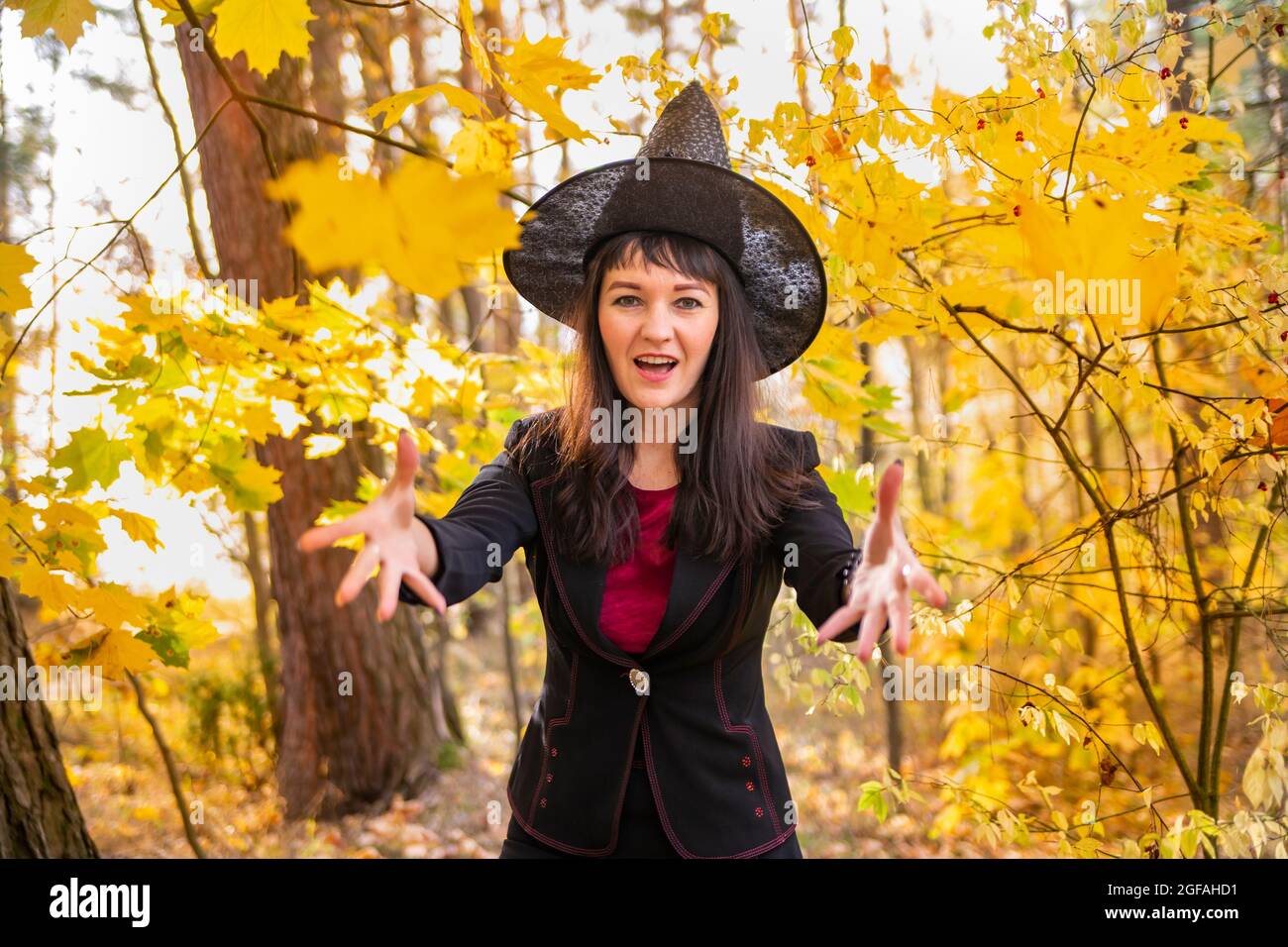 witch making magic. woman in a witch costume laughs and throws leaves ...