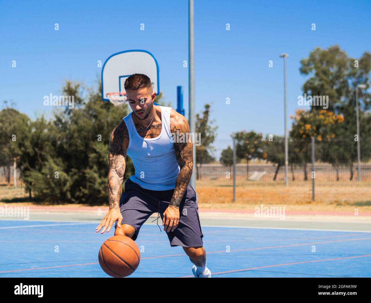 Athletic handsome Spanish basketball player training on a basketball ...