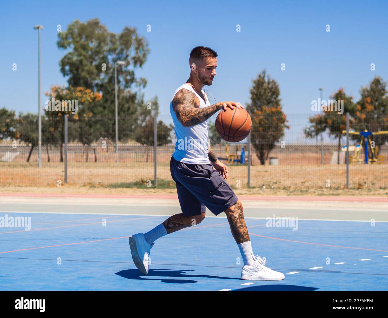 Athletic handsome Spanish basketball player training on a basketball ...