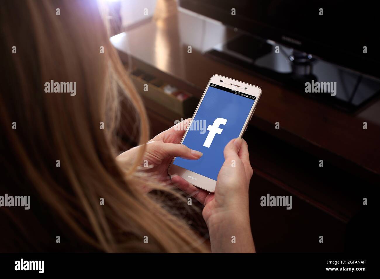 Girl with smartphone in her hands and a Facebook logo on the screen ...
