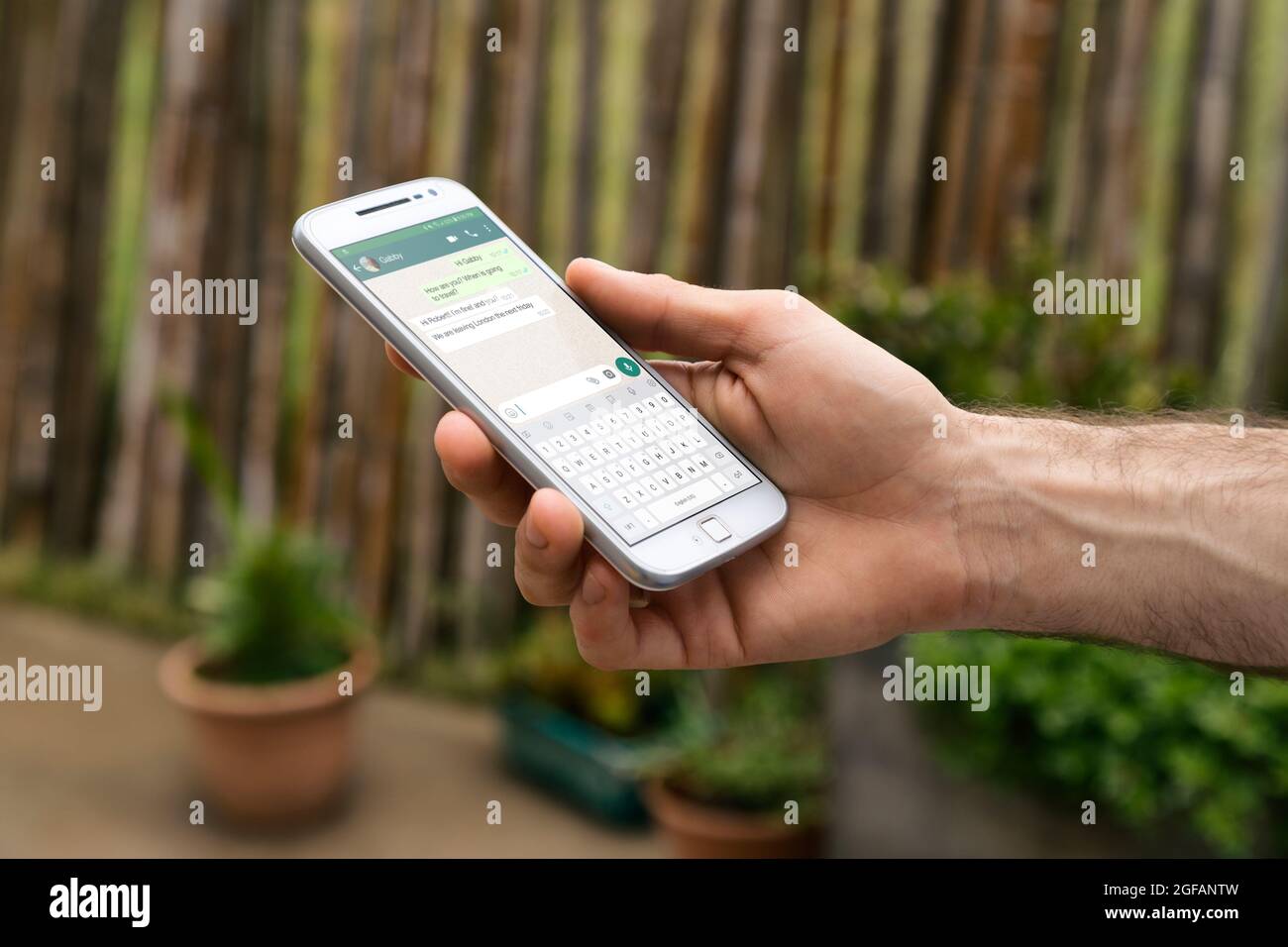 Man with a white cell phone in his hand. On the screen you can see the ...