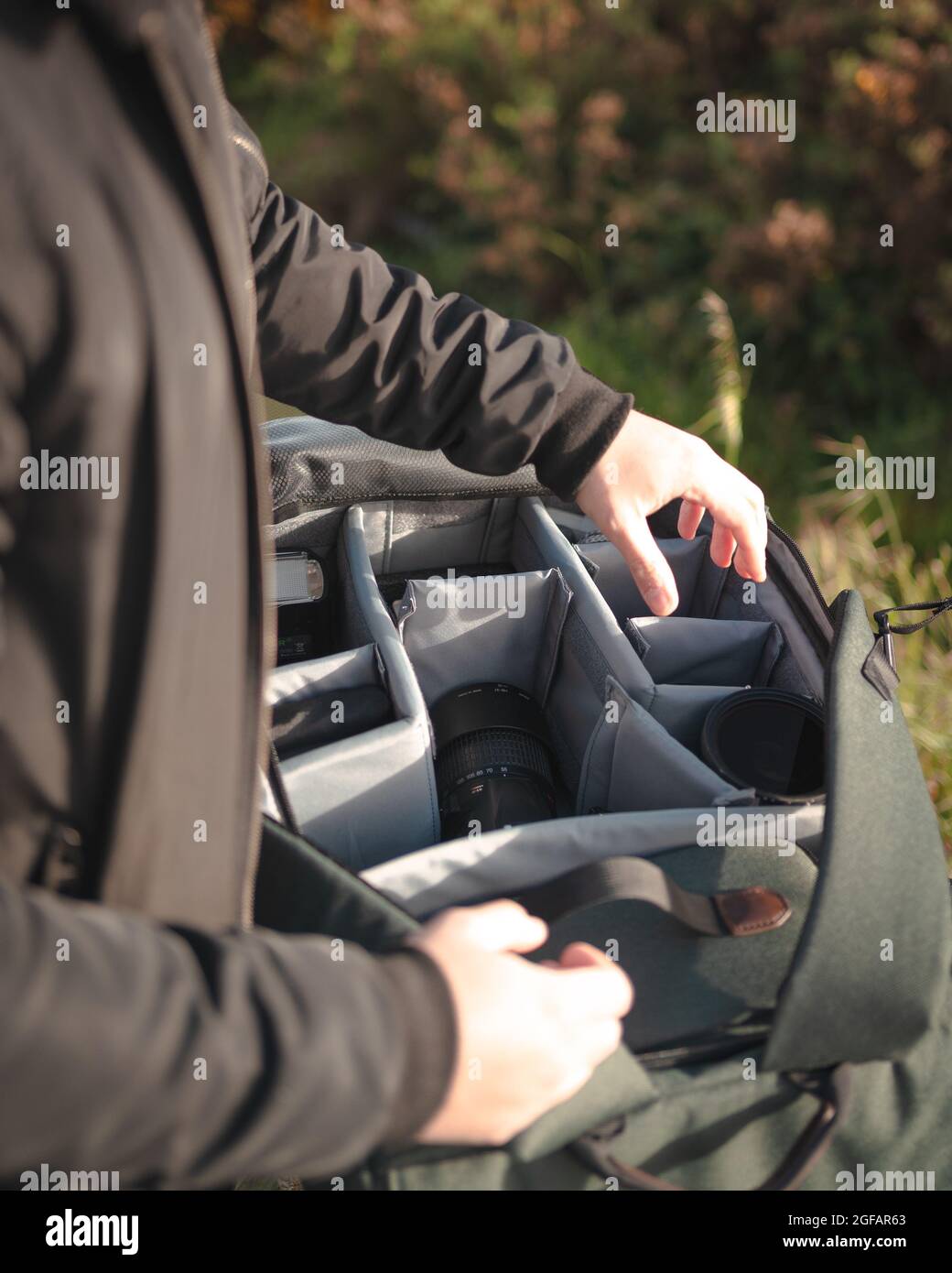 Vertical closeup of a man opening a bag with photography equipment ...