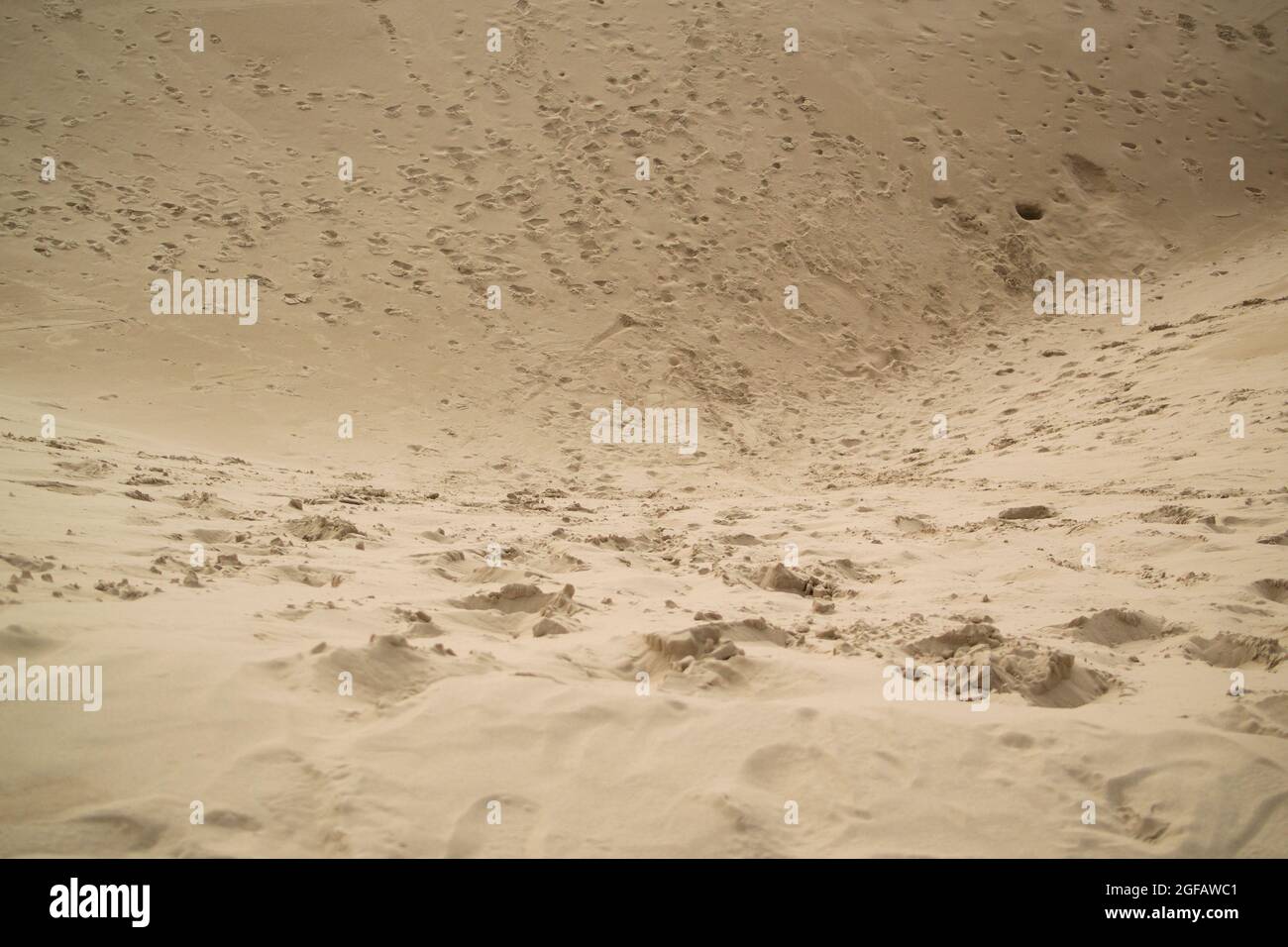 Footprints traversing a crater in a sand dune. Signs of people running ...