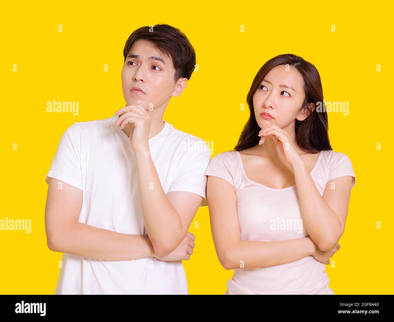 Young man and woman thinking and looking aside.Isolated on yellow ...