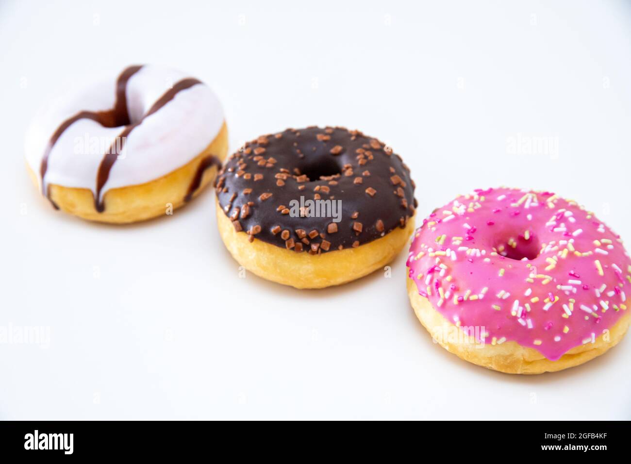 Closeup of three different-colored donuts placed close together in a ...