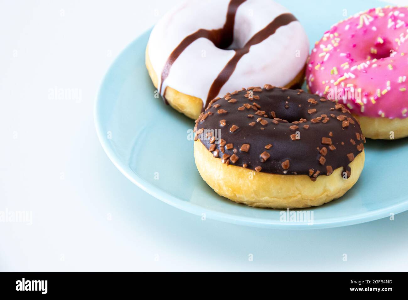 Closeup of three delicious donuts on a ceramic plate in front of an ...