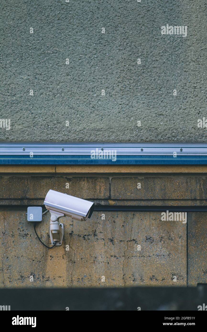 Close up of a white security camera hanged on a brown wooden surface ...