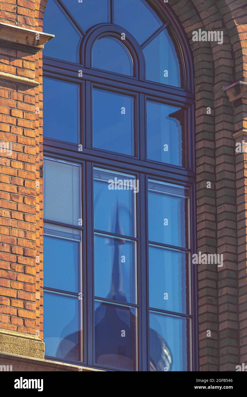 Vertical shot of blue window reflecting glass in the frame of red ...