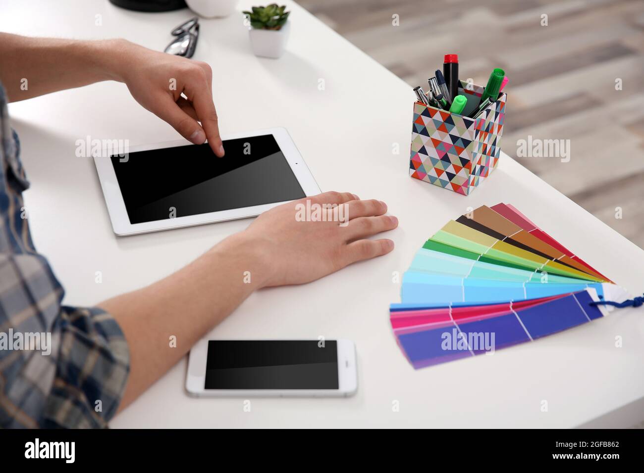 Man working with color palette and tablet at office Stock Photo - Alamy